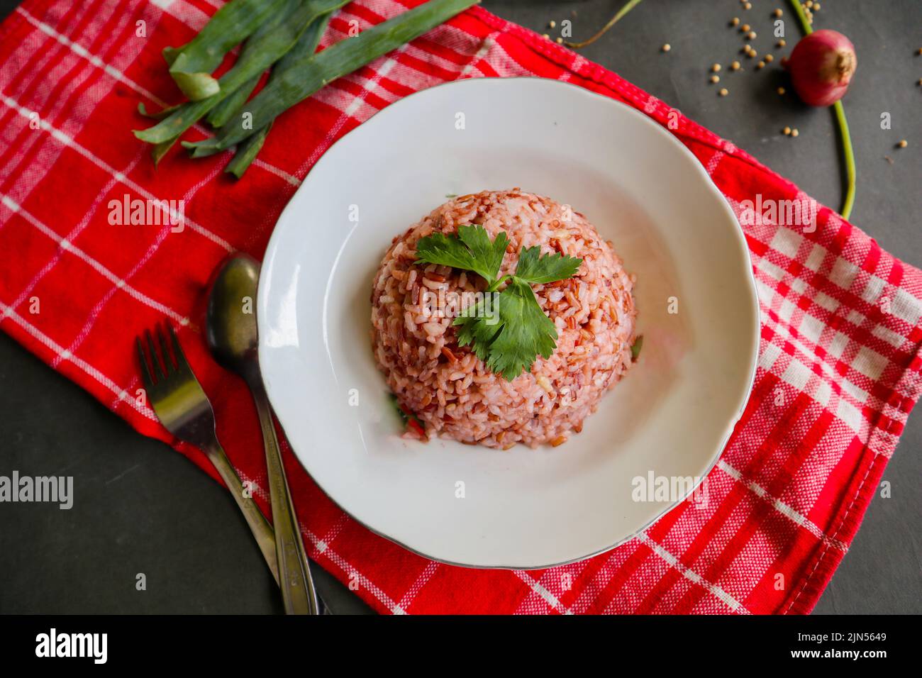 Red steamed rice or nasi merah served in plate isolated on black ...