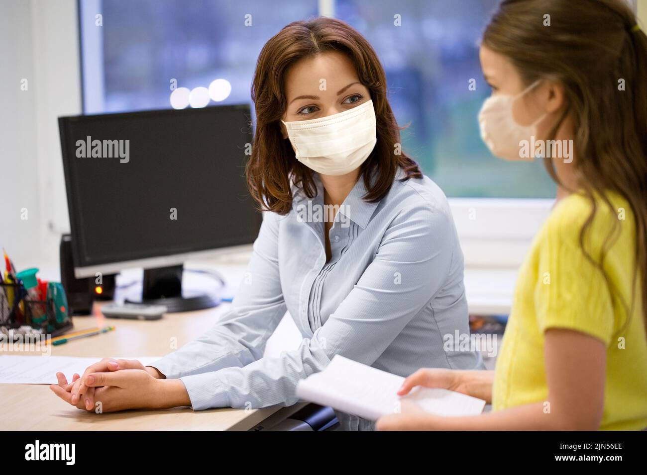teacher and student girl in masks at school Stock Photo - Alamy