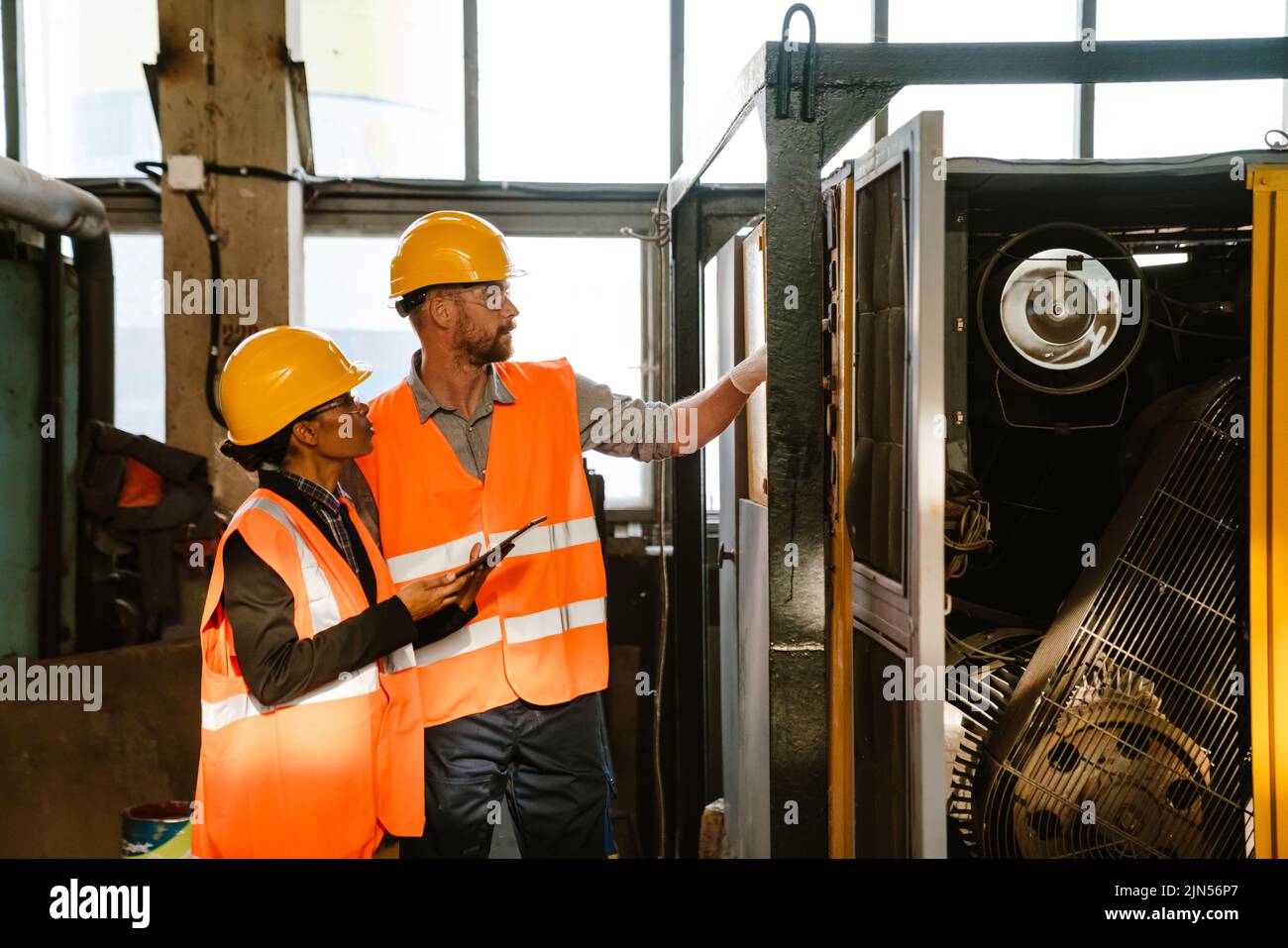 Multiracial man and woman in protective clothing working with equipment ...
