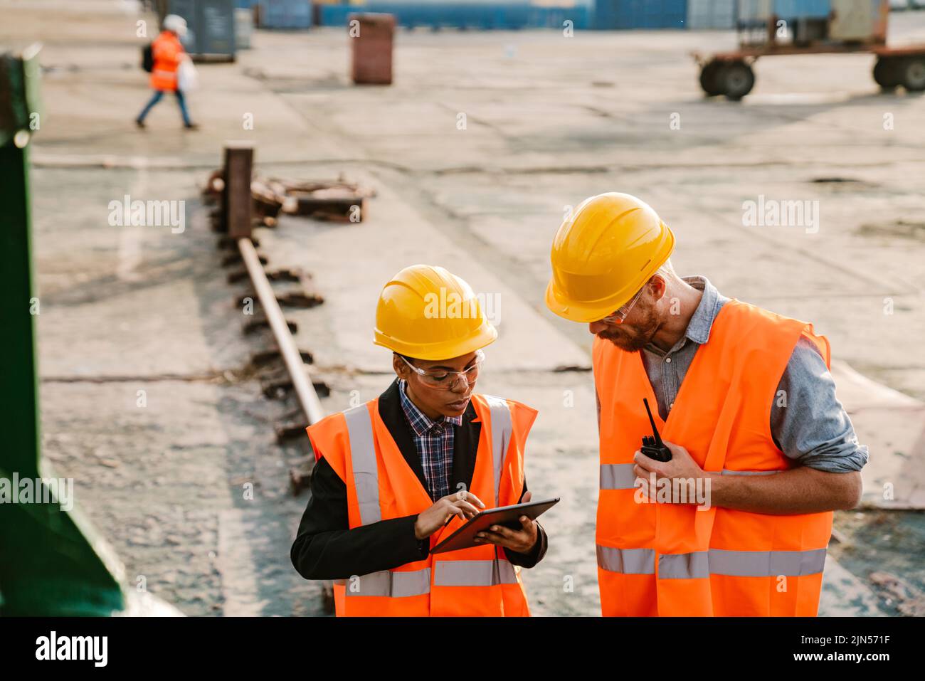 Multiracial man and woman wearing helmets working with tablet-computer ...