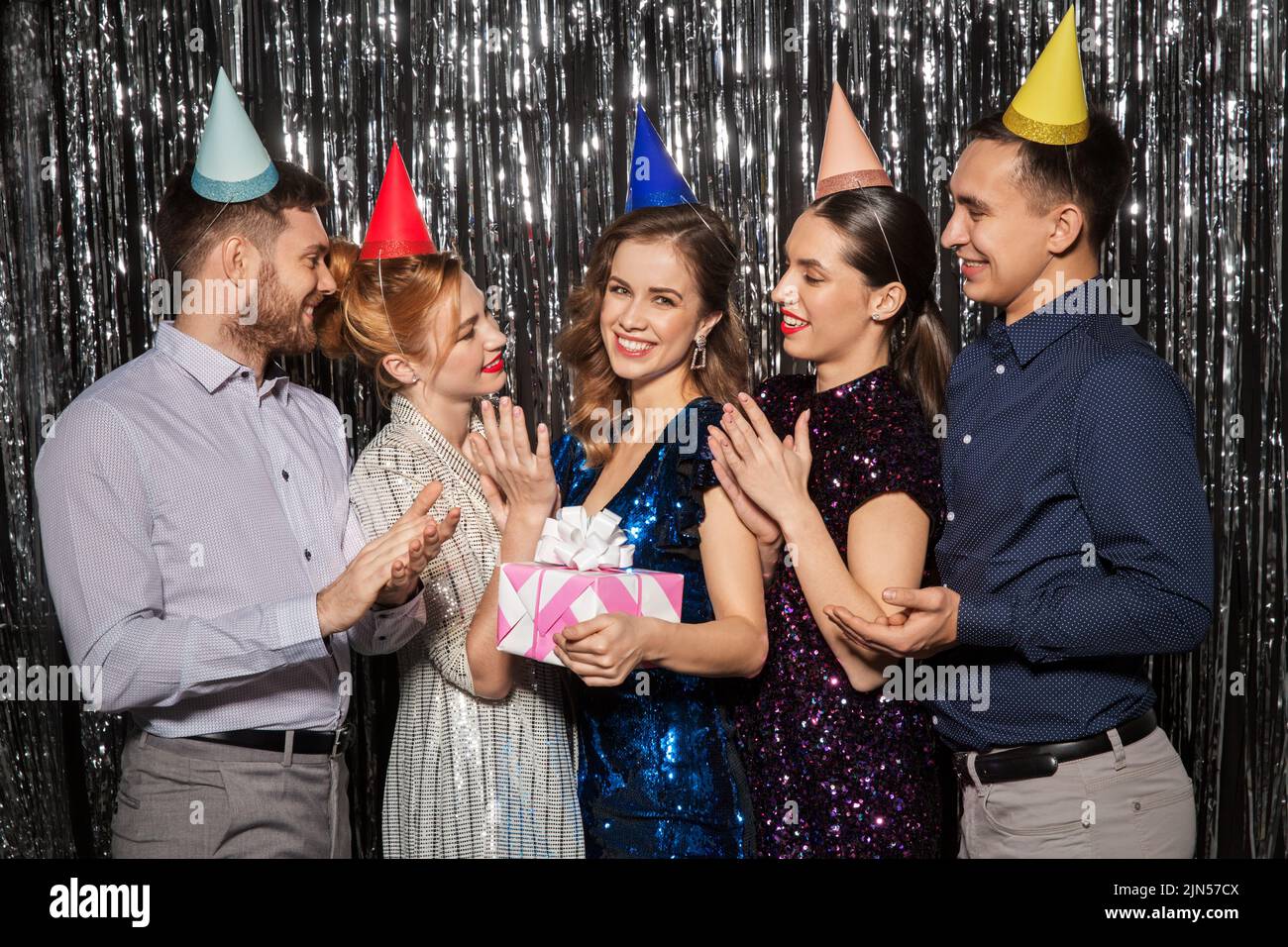 happy friends in party hats with birthday gift Stock Photo - Alamy