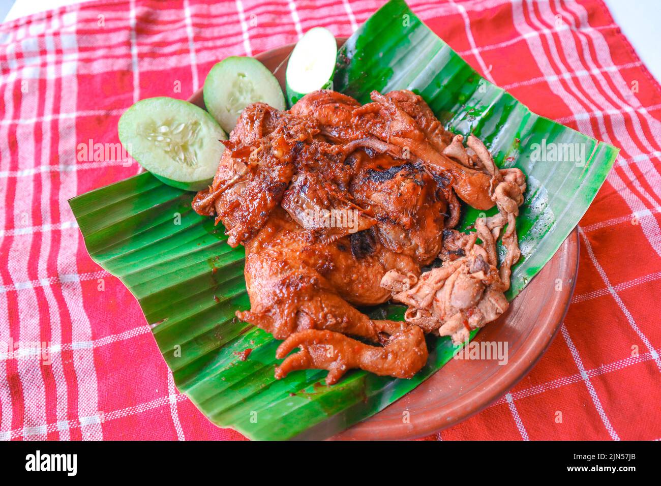 grilled chicken or ayam bakar with cucumber slash served on banana leaf ...