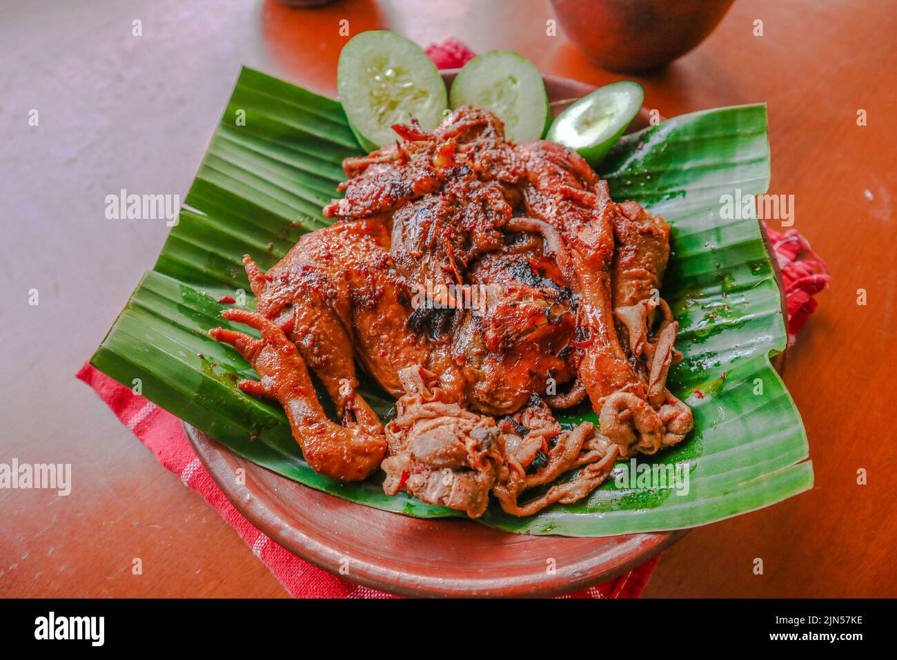grilled chicken or ayam bakar with cucumber slash served on banana leaf ...