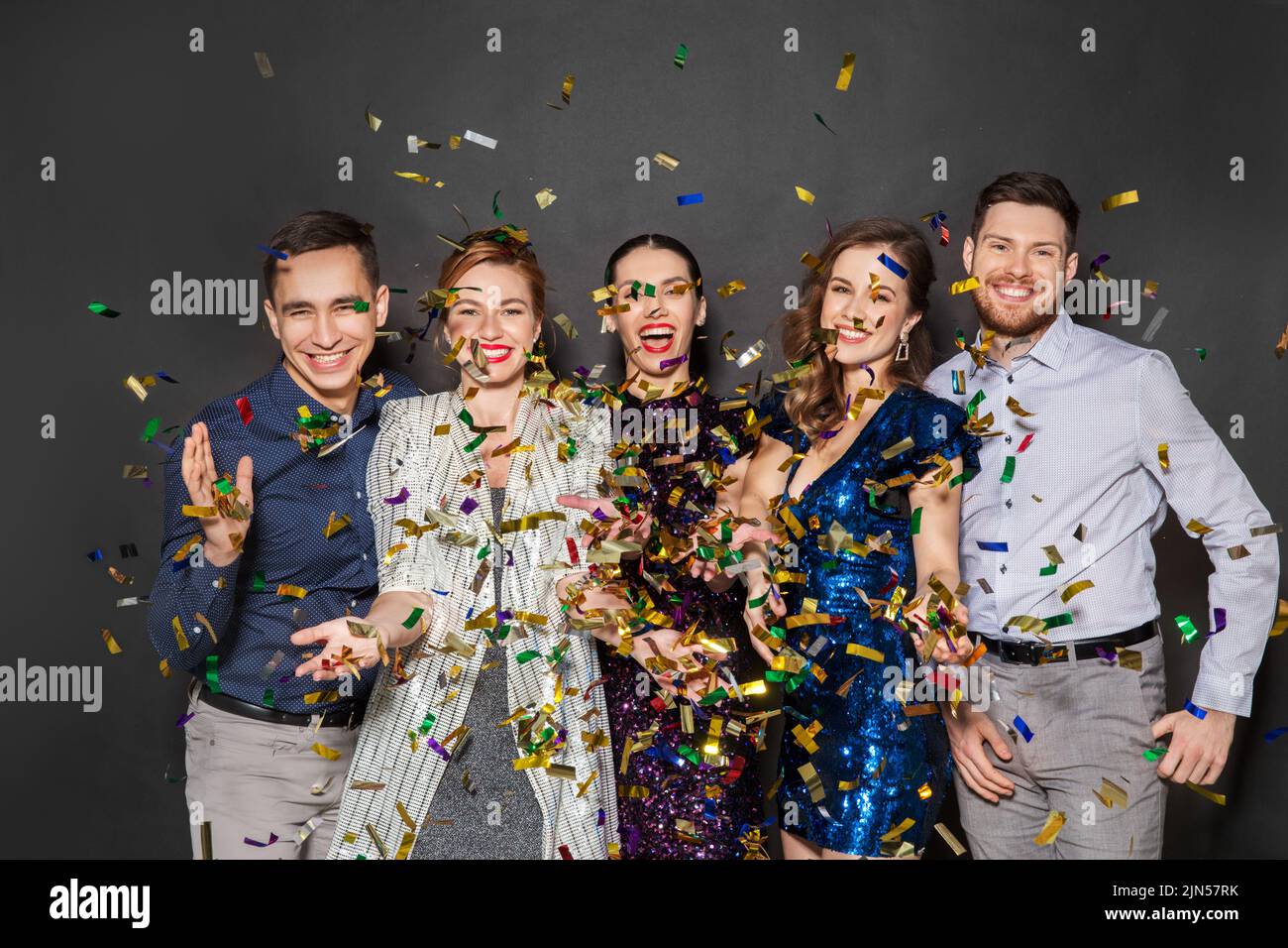 happy friends at party under confetti over black Stock Photo - Alamy