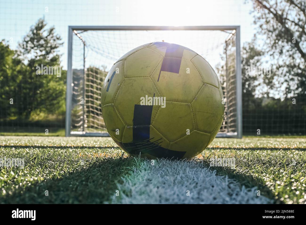 Yellow ball placed on the penalty spot in front of empty goal posts on ...