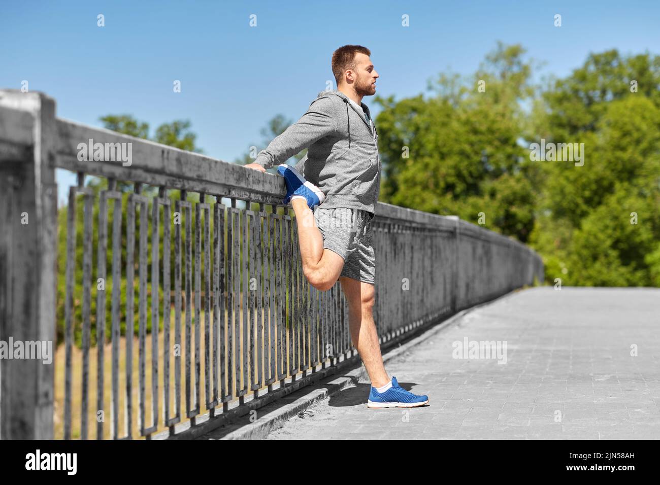 man stretching leg on bridge Stock Photo - Alamy