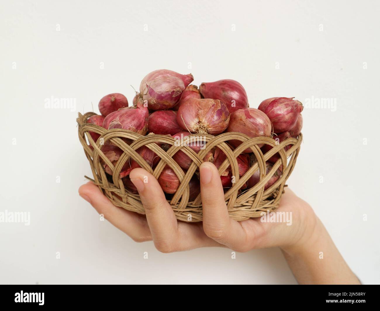 Hand holding a collection of onions in a small rattan basket Stock ...