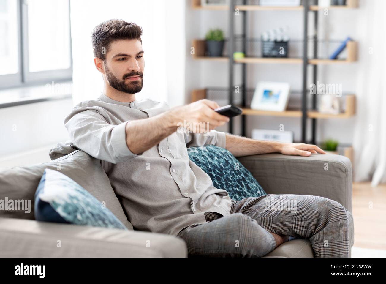 man with remote control watching tv at home Stock Photo - Alamy