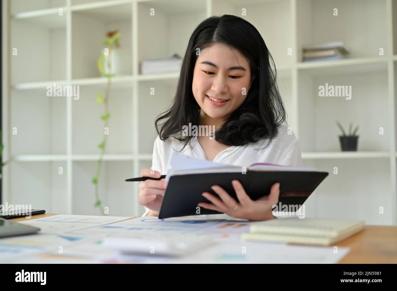 Attractive young Asian female accountant or financial worker reviewing ...