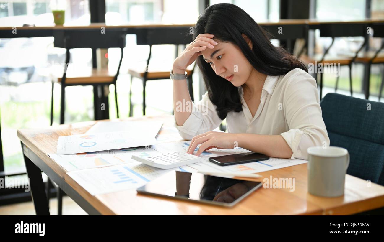 Young Asian businesswoman or female accountant, stressed and thoughtful ...