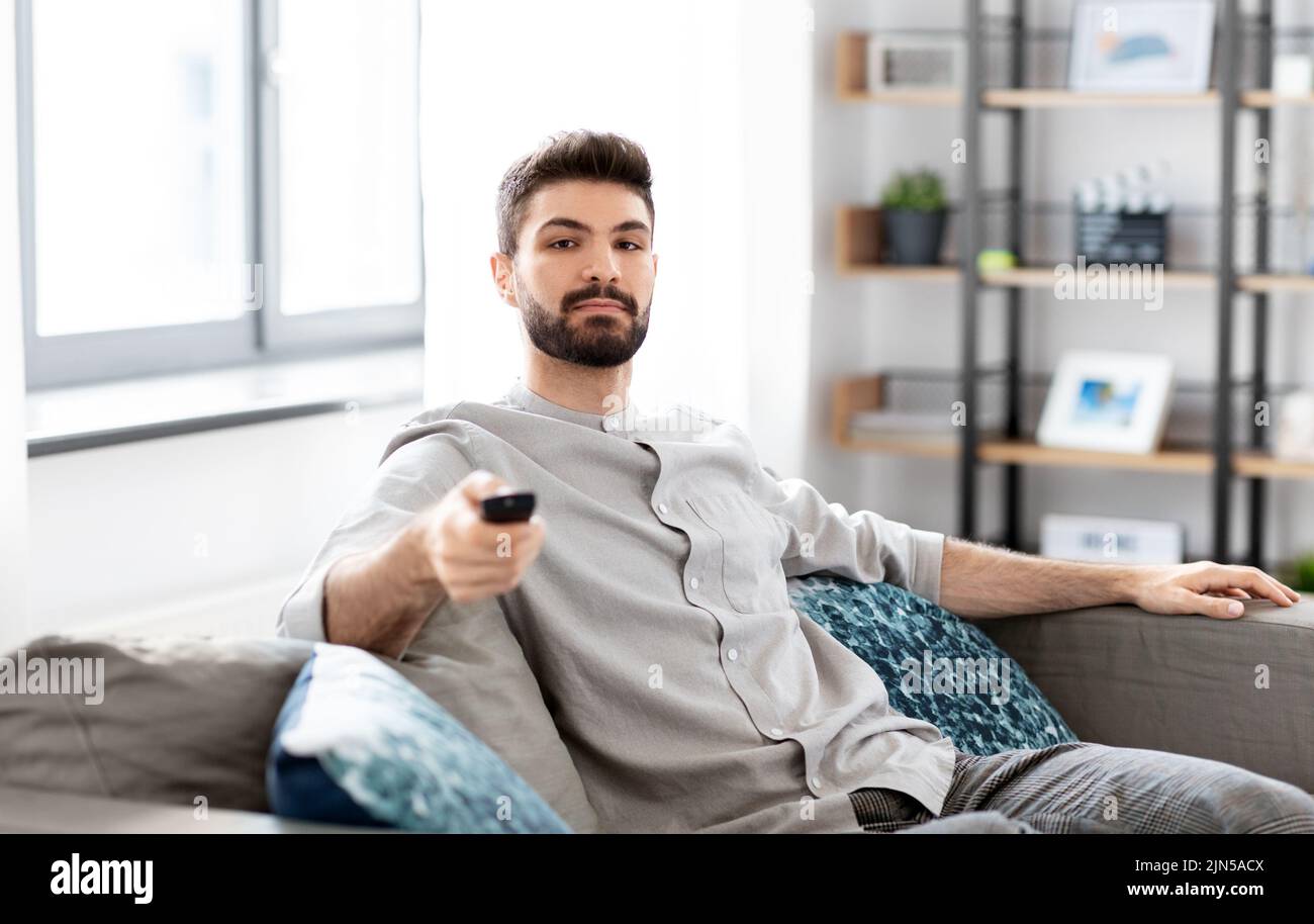 man with remote control watching tv at home Stock Photo - Alamy