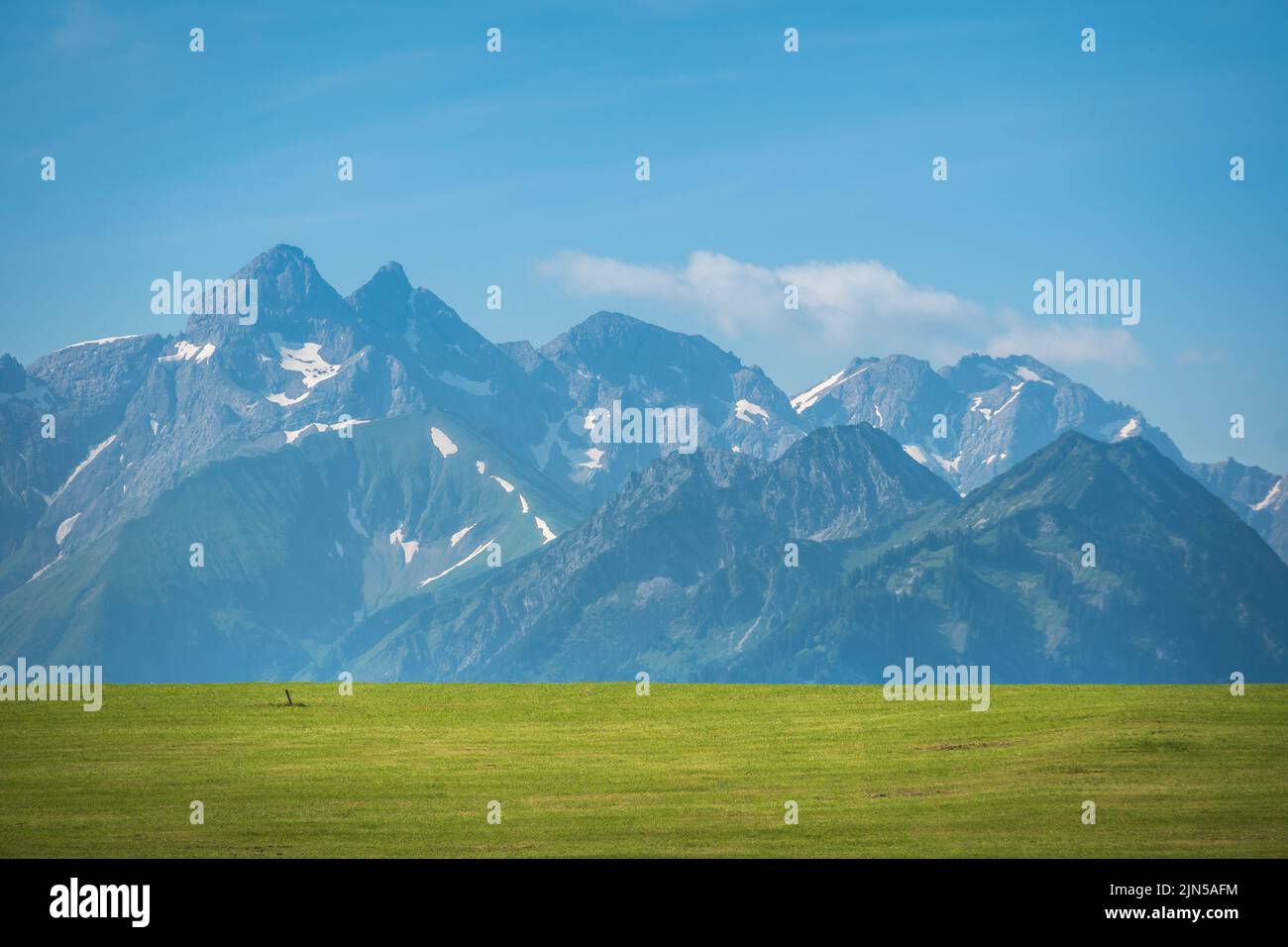 A beautiful landscape of smooth grassland with pointy mountains in the ...