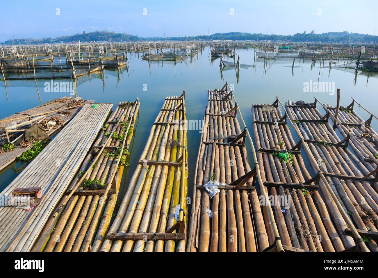 bamboo raft leaning against a lake among traditional fish cages in ...