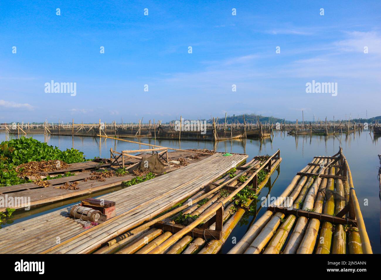 bamboo raft leaning against a lake among traditional fish cages in ...