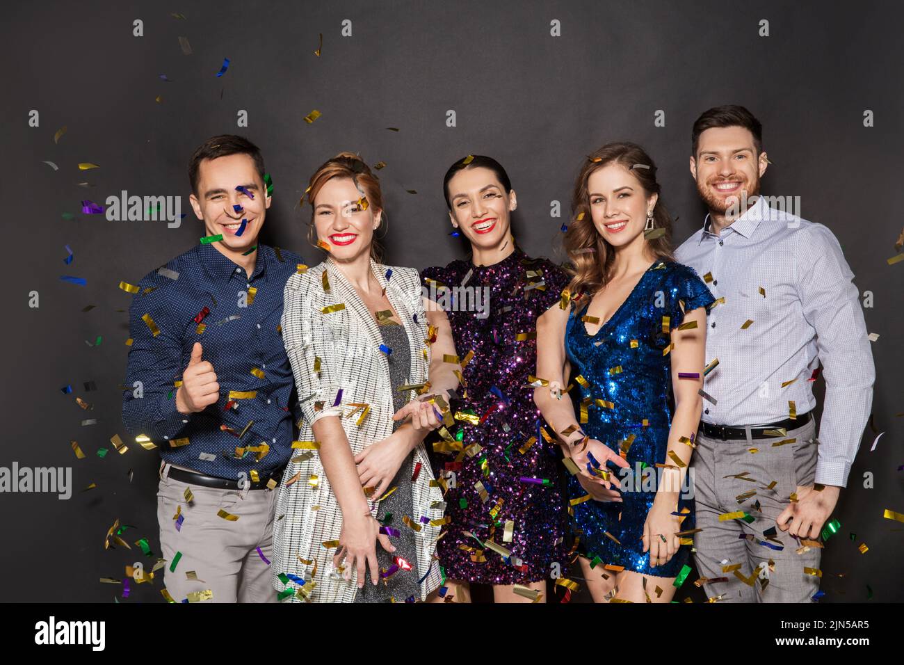 happy friends at party under confetti over black Stock Photo - Alamy