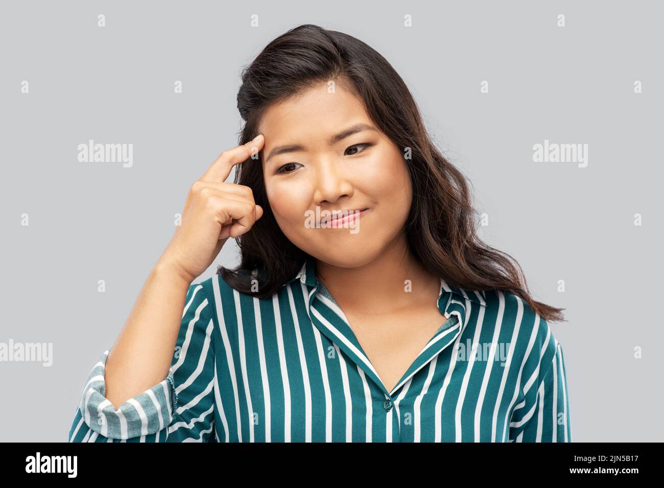 thinking asian woman over grey background Stock Photo - Alamy