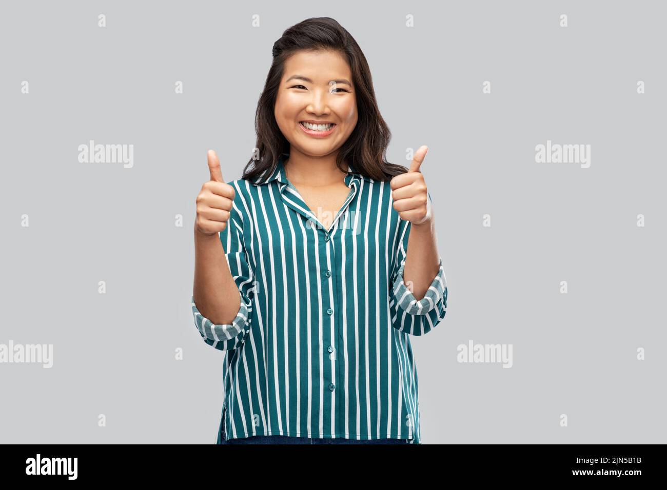 happy asian woman showing thumbs up over grey Stock Photo - Alamy