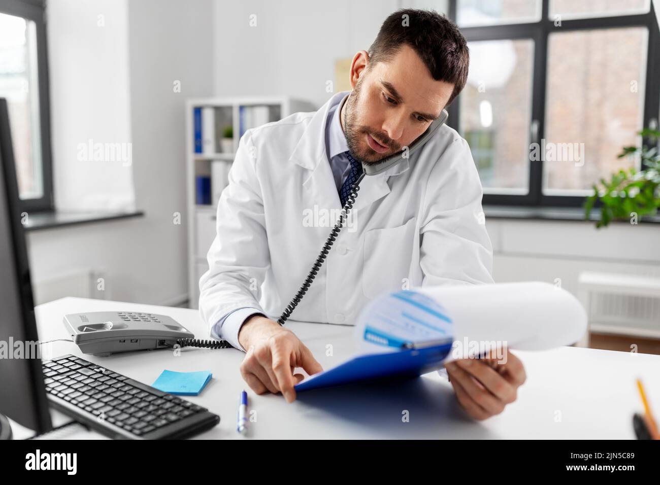 male doctor calling on desk phone at hospital Stock Photo - Alamy