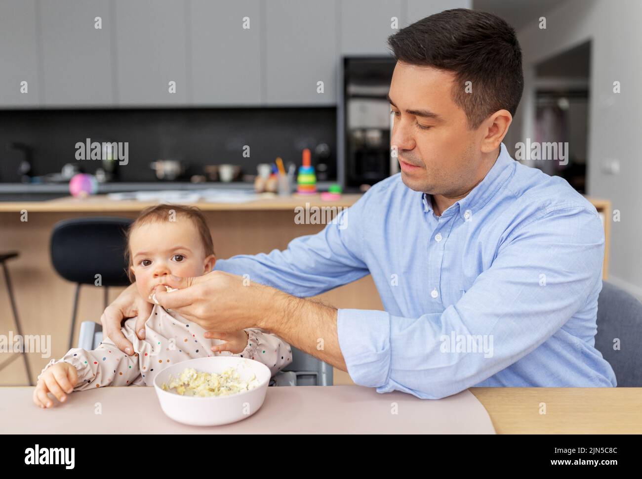 middle-aged father feeding baby daughter at home Stock Photo - Alamy