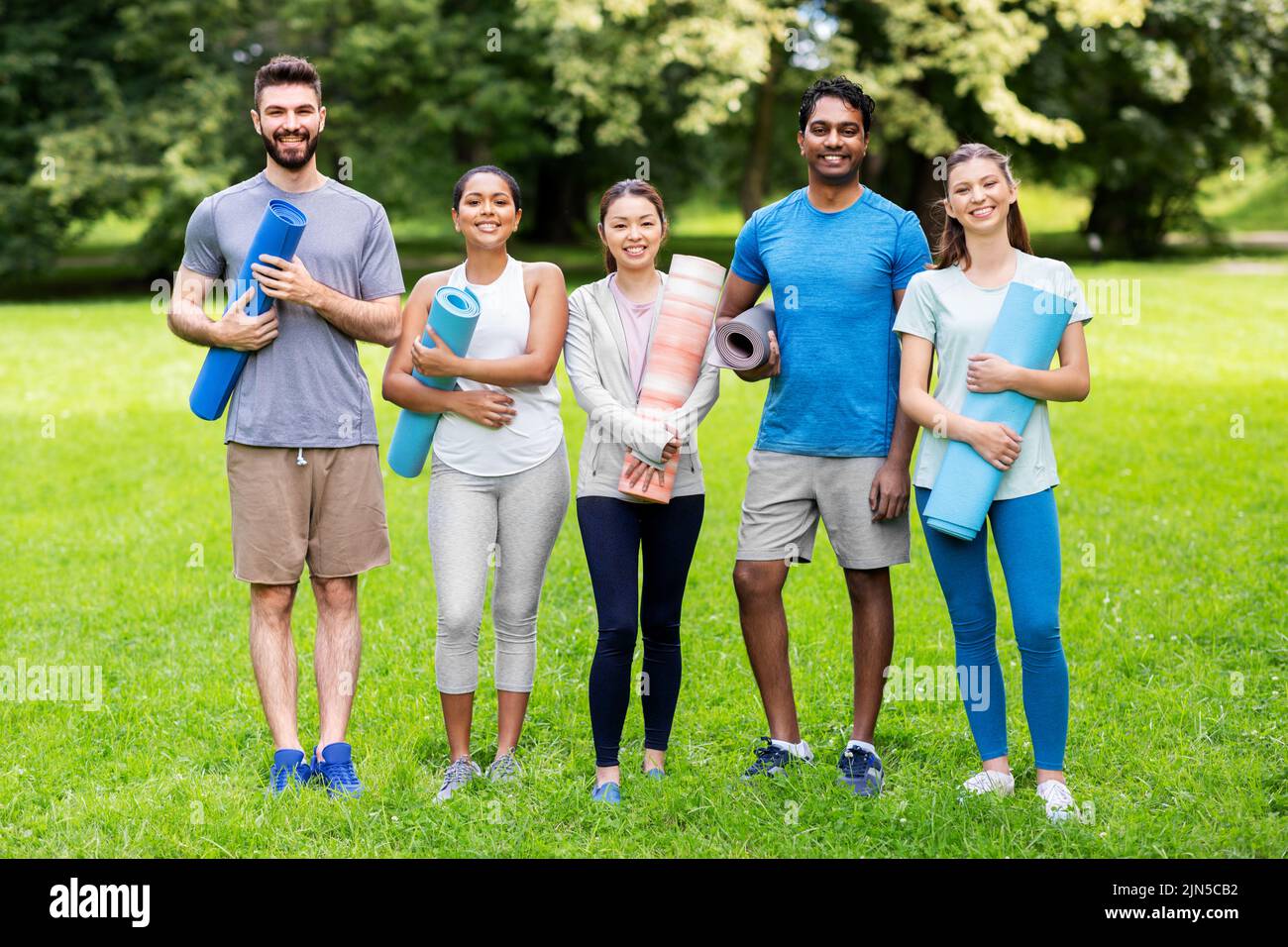 group of happy people with yoga mats at park Stock Photo - Alamy