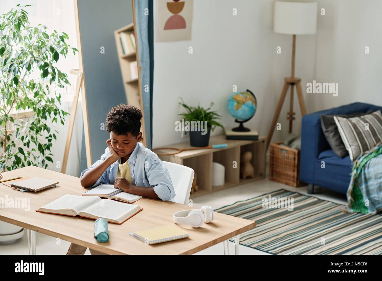 African little boy sitting at desk in his room and preparing his ...