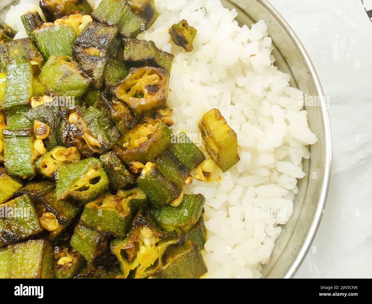 Cooked rice and some vegitable in a plate. A steel place containing ...