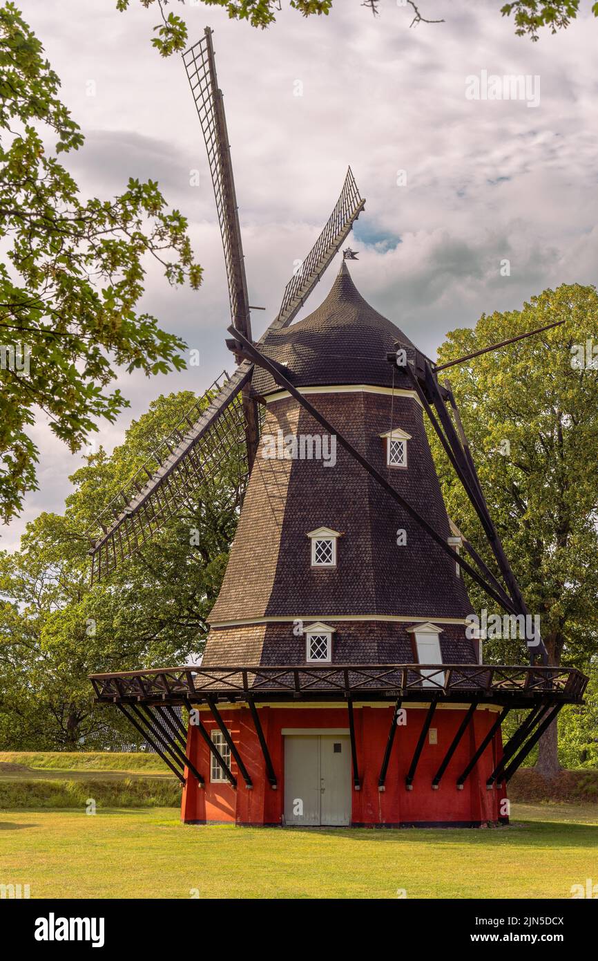 A vertical shot of a traditional windmill surrounded by trees in ... A vertical shot of a traditional windmill surrounded by trees in ...