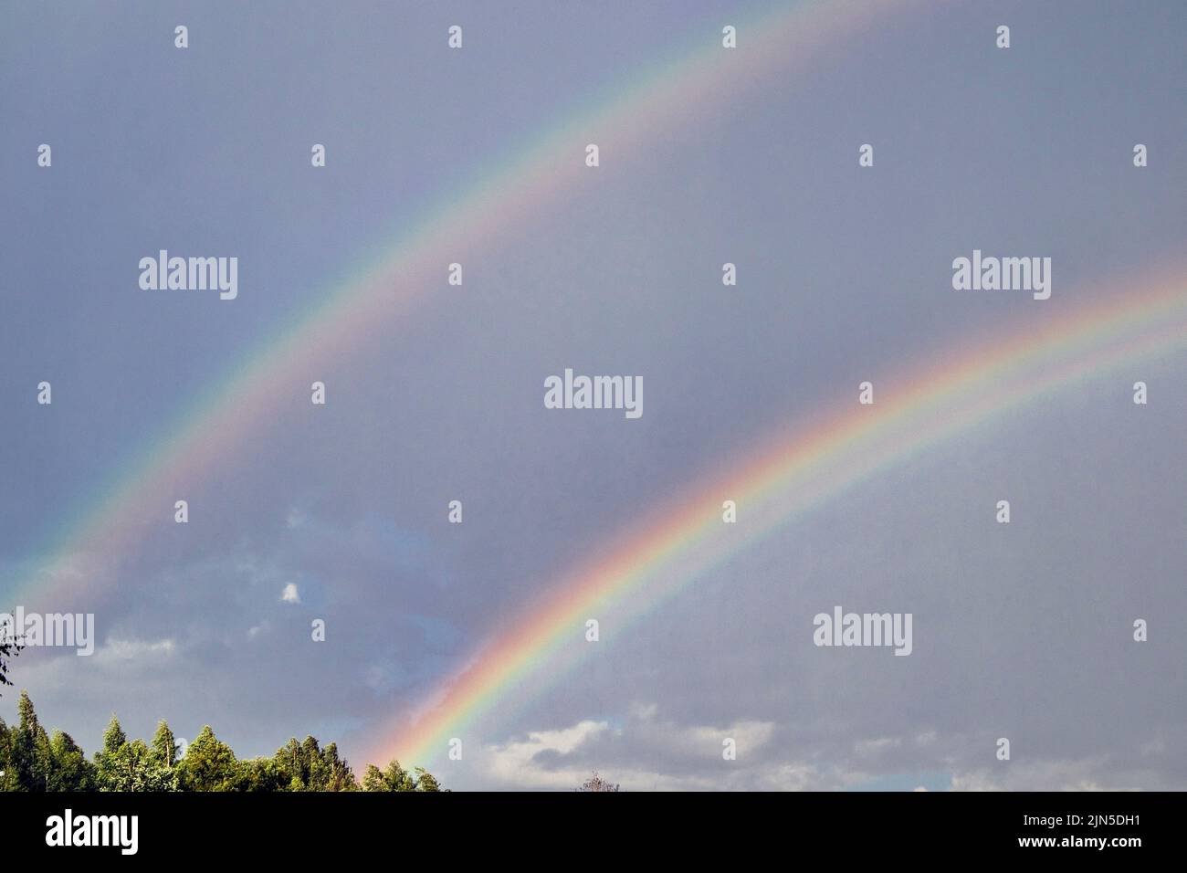 double rainbow in a cloudy sky after heavy rain Stock Photo - Alamy
