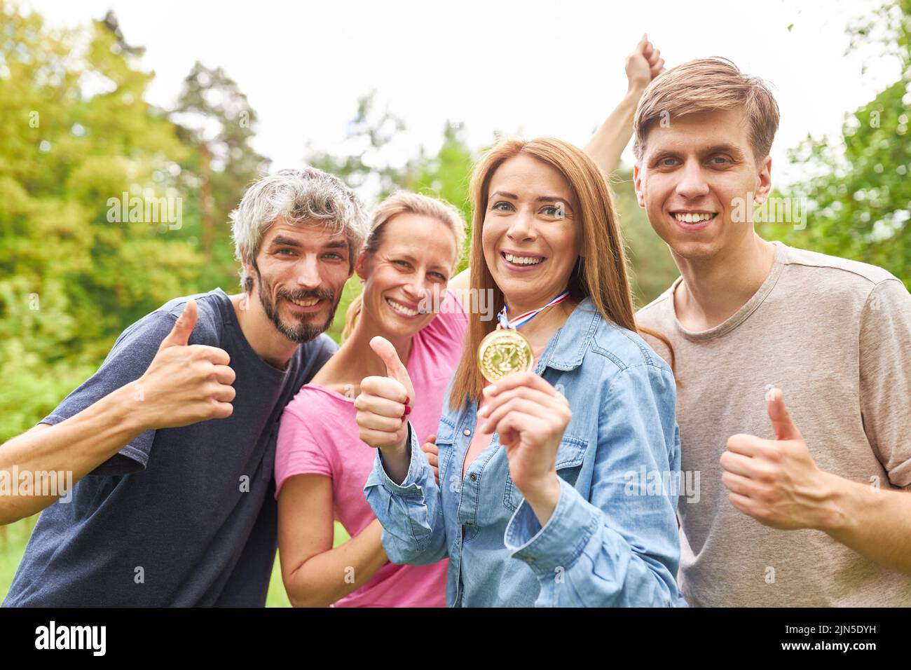 Young people as a successful winning team with a medal celebrate ...
