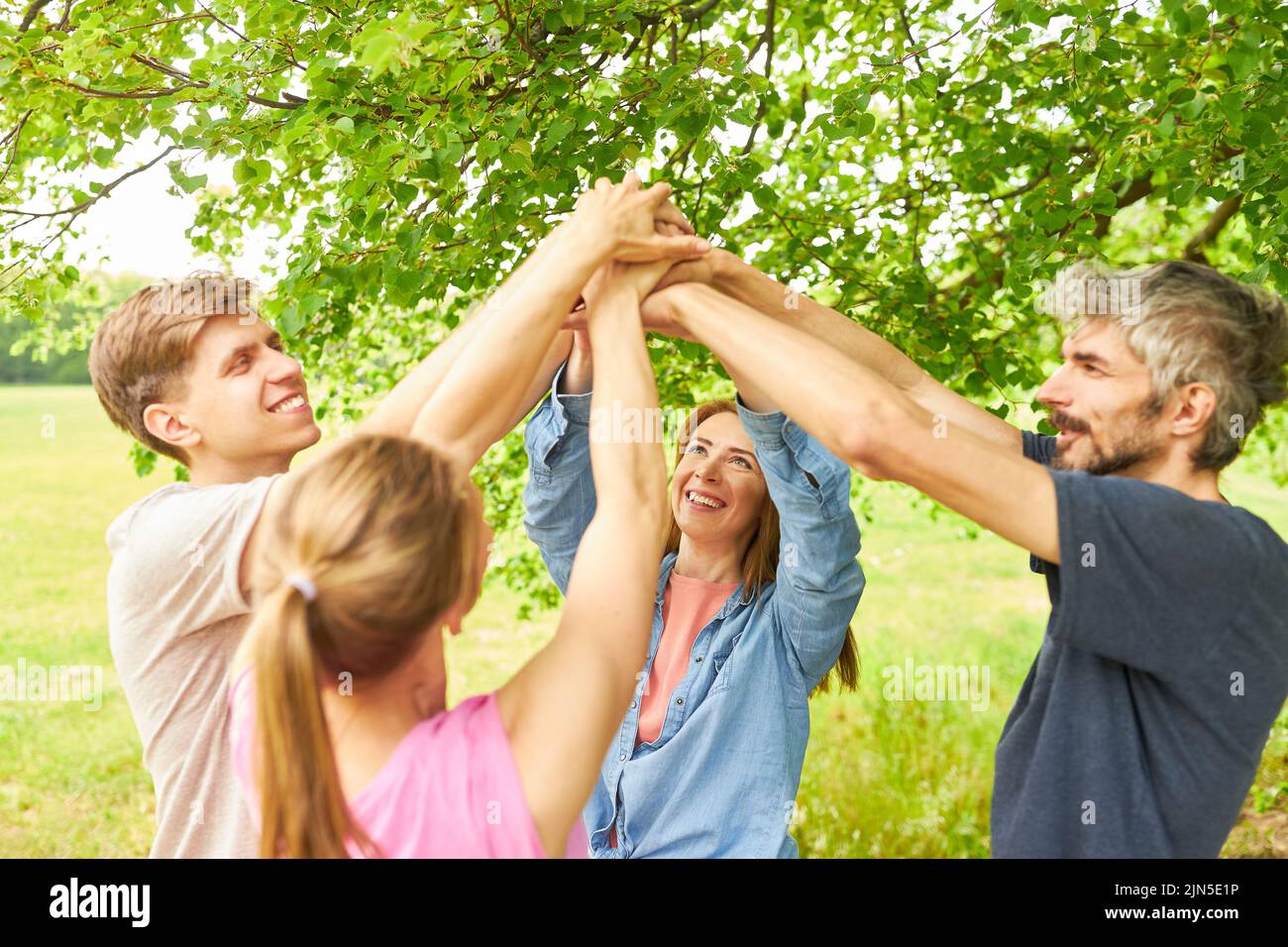 Four people stack hands in team building workshop for synergy and ...