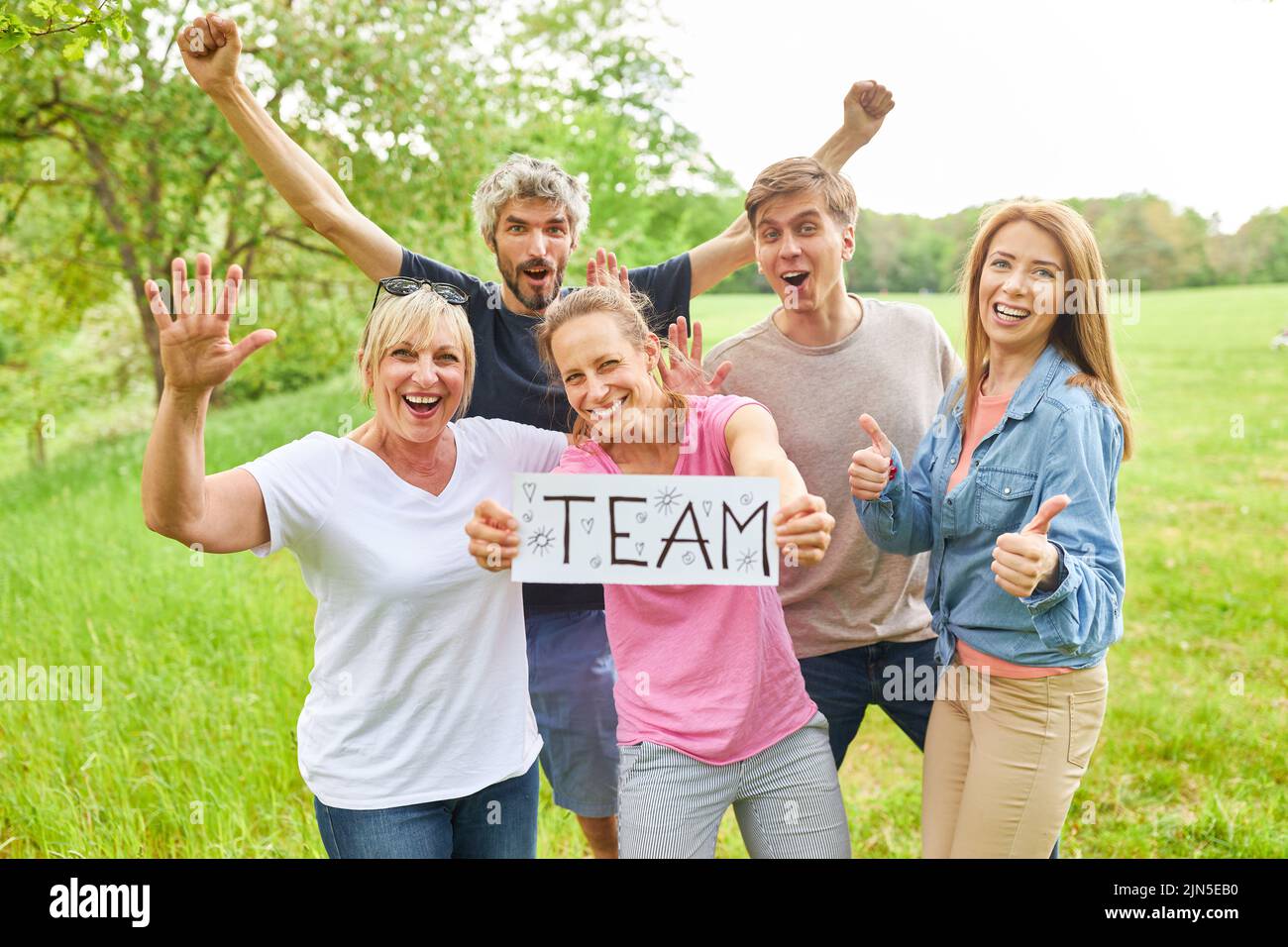 Group of young people celebrating a success and holding up a sign with ...