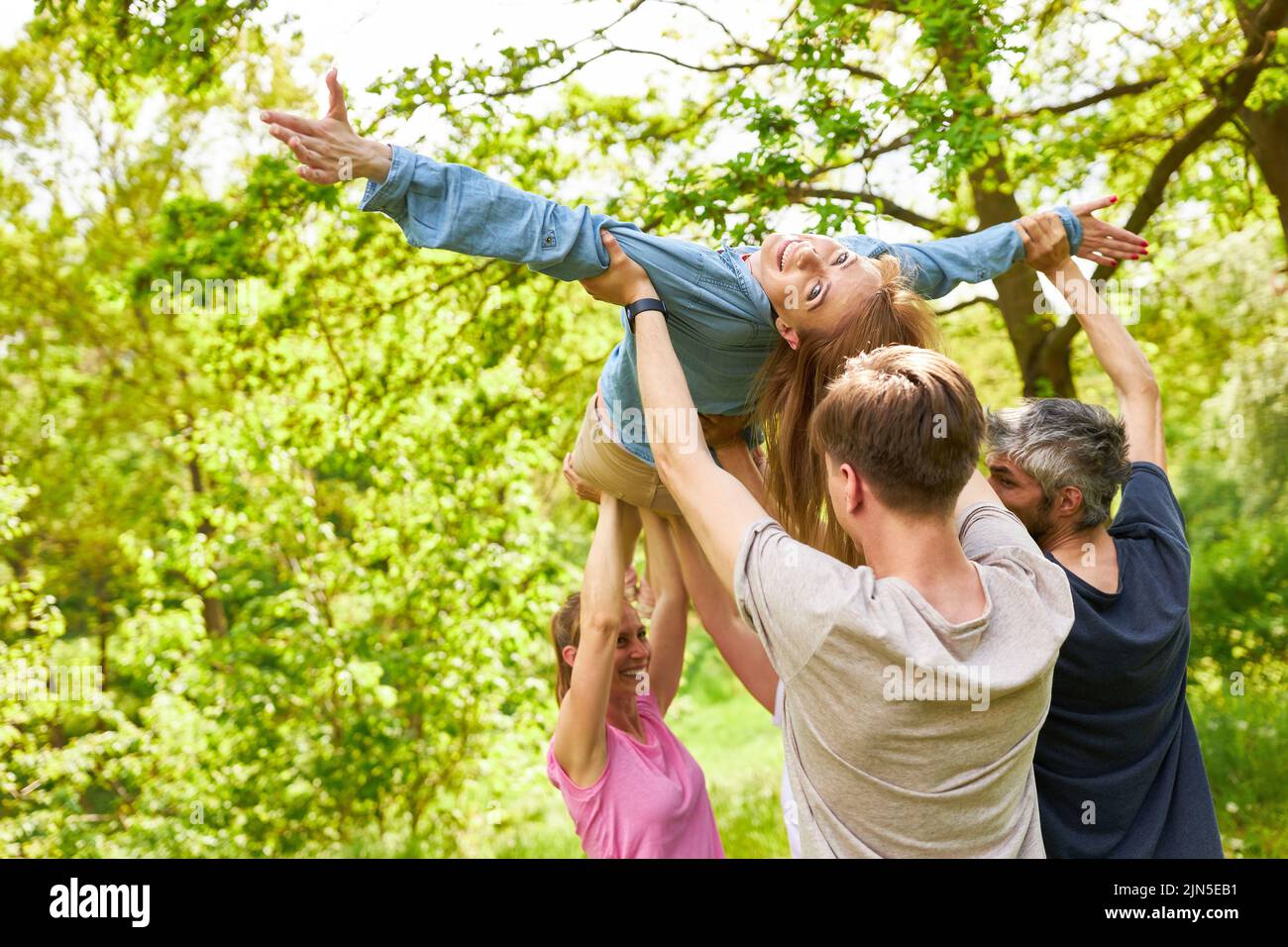 Woman being held and lifted high by colleagues as an exercise in ...