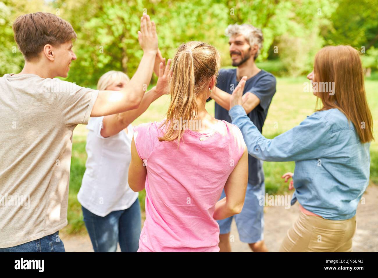 Young people stand in a circle giving a high five as an exercise in ...