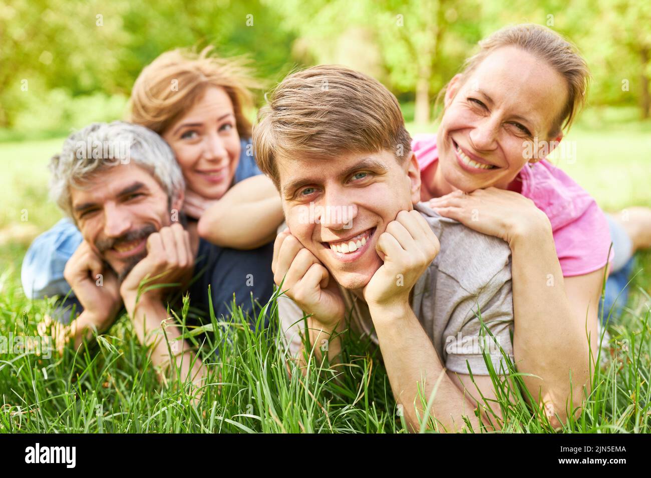 Two happy couples lie together on a meadow for relaxation on vacation ...