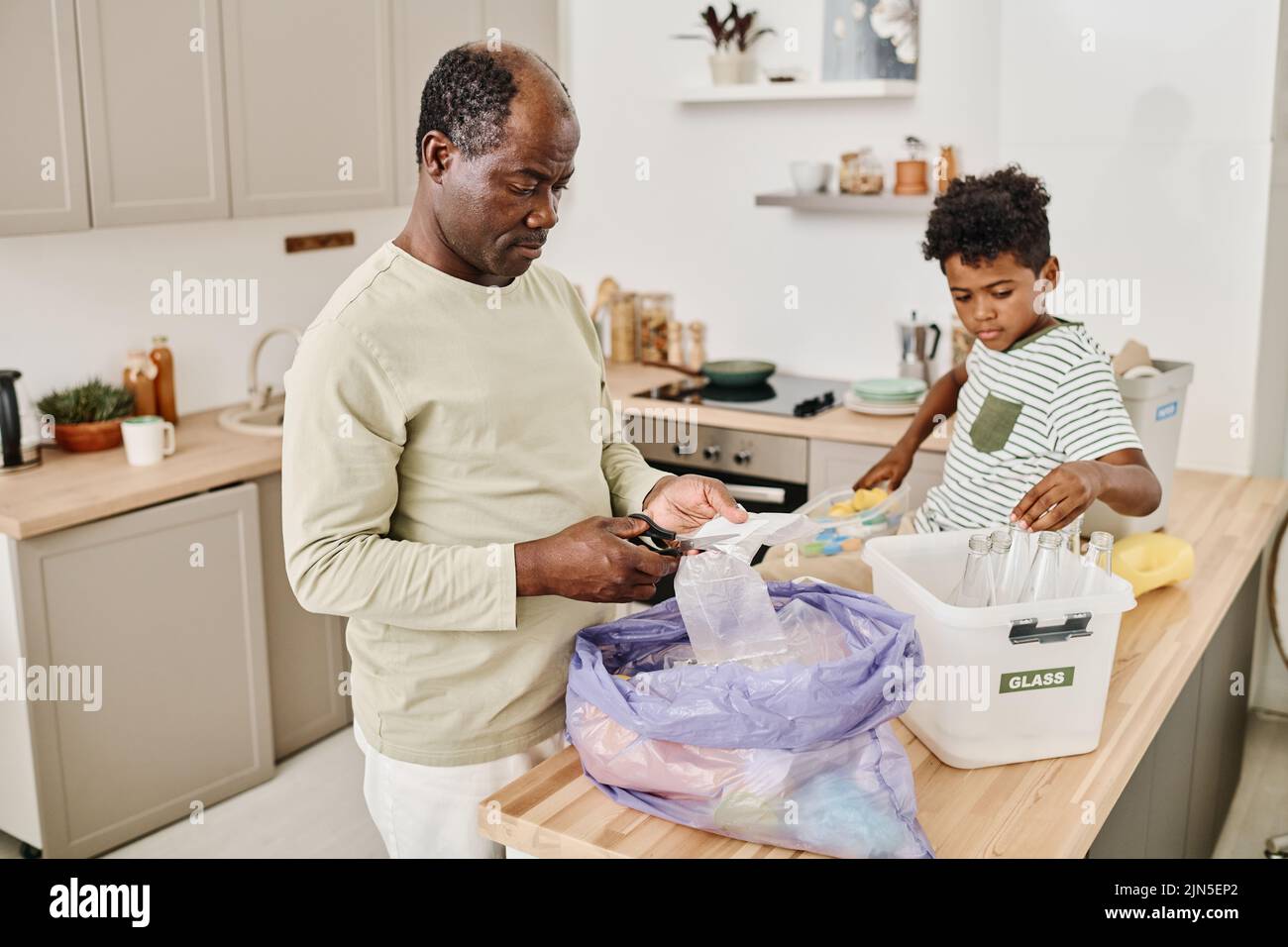 African dad separating garbage in package and containers together with ...