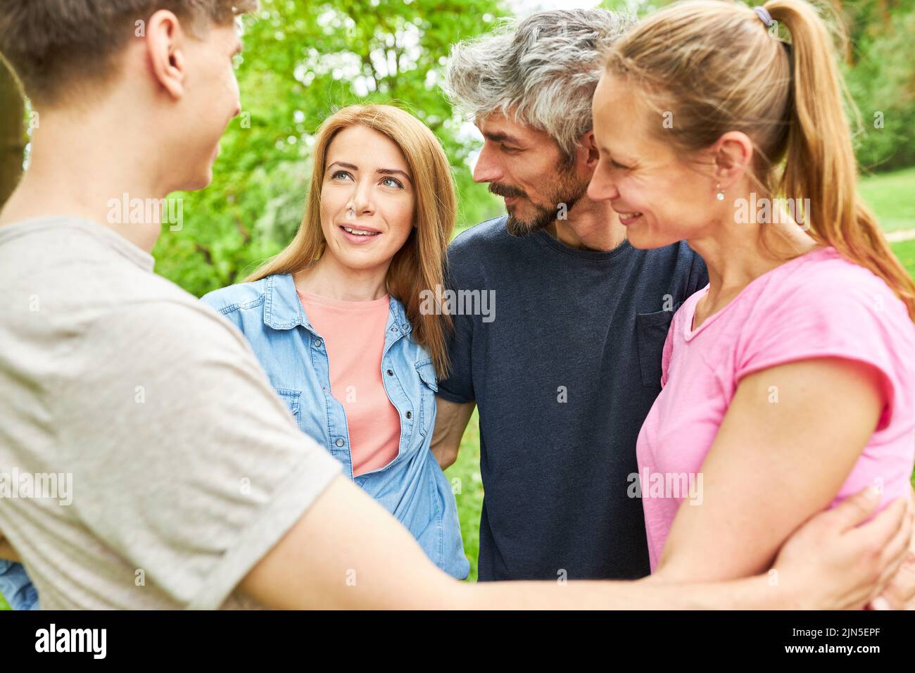 Young people stand in a circle and talk to each other as friends on a ...