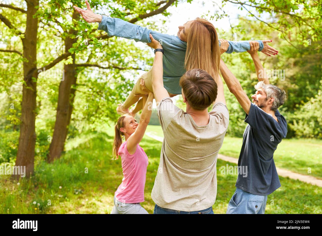 Young people lifting a woman up together in team building outdoor ...