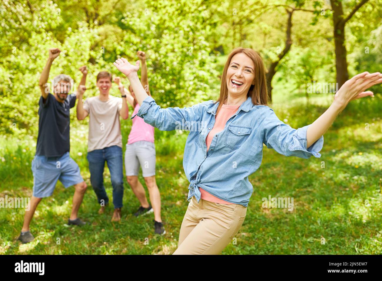 Happy young woman and team cheering after a success in outdoor ...