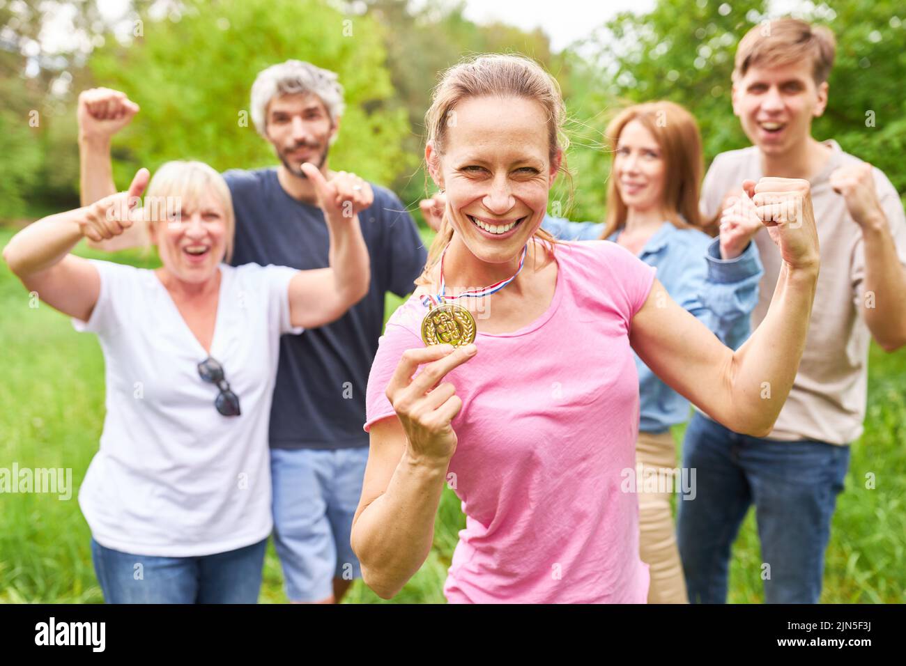 Young woman with winners medal proudly cheering with clenched fists ...