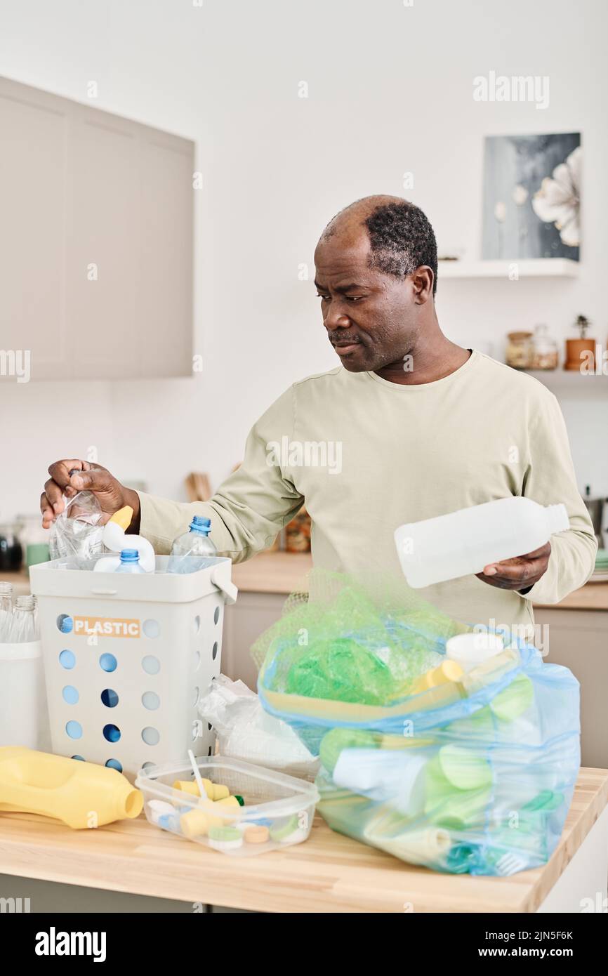 African man separating garbage in different containers at table in the ...
