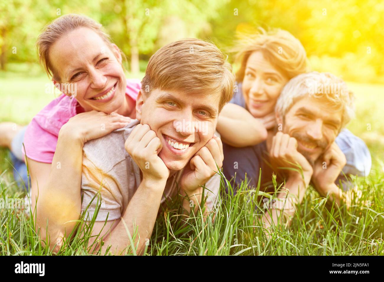 Happy friends lying together in park in summer for rest and relaxation ...