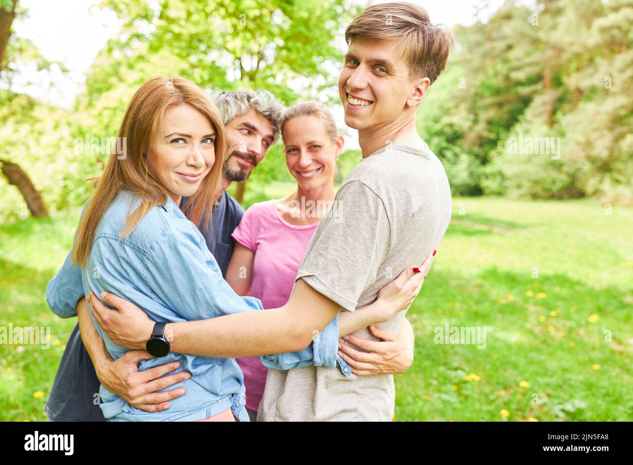Young people hug each other on a summer meadow for friendship and ...