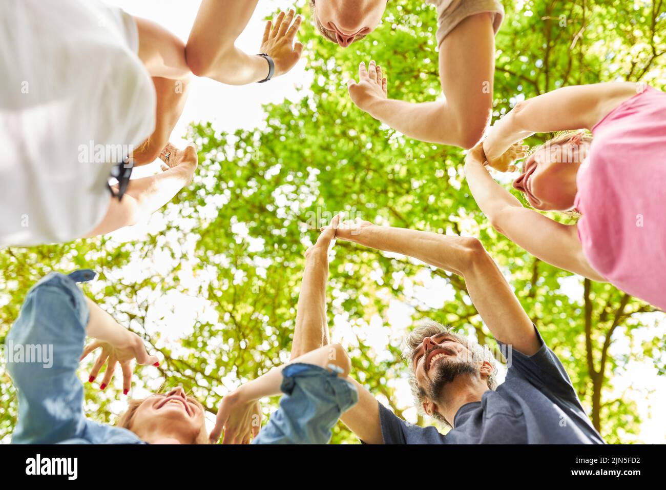 Group of young people standing in circle with raised hands at team ...