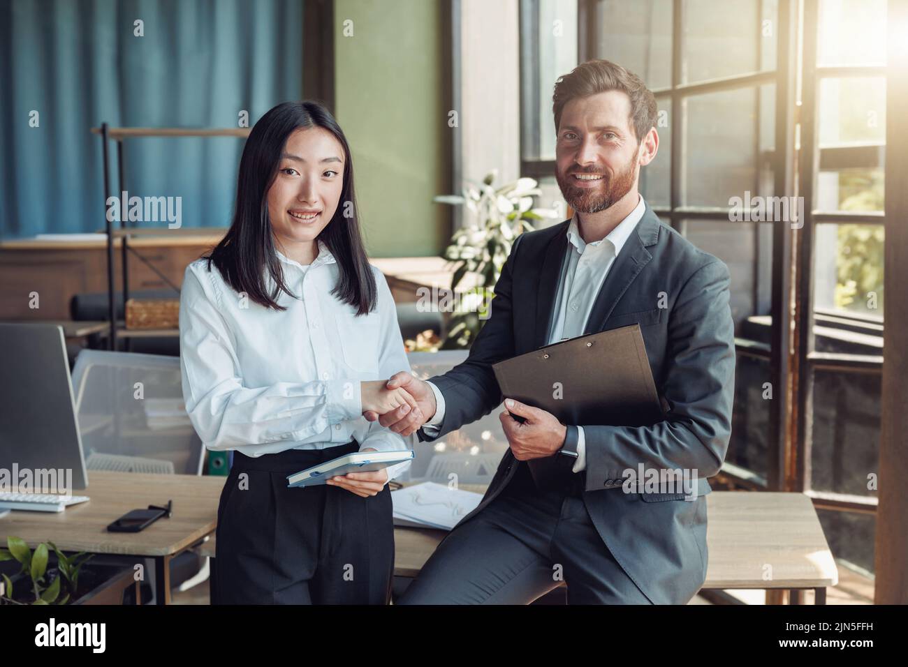 Two happy business colleagues clap hands after finishing work on ...