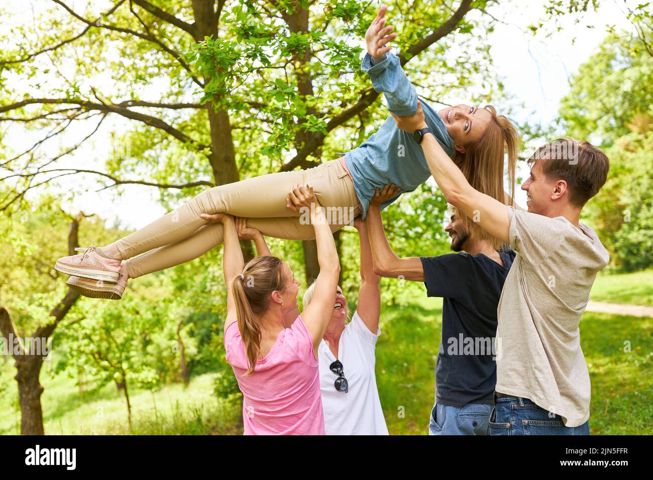 Successful team of young people carries a young woman in team building ...