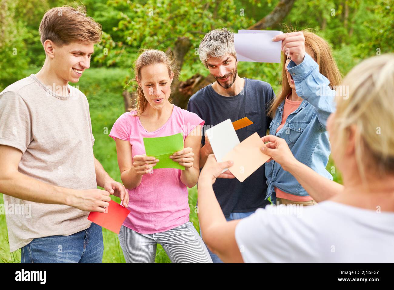 Group of young people playing team building game with colorful cards ...