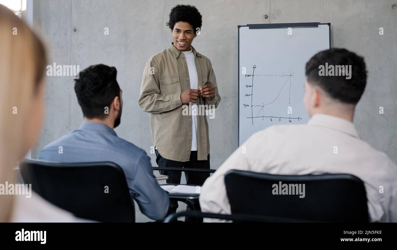 Young male manager presenting project plan to colleagues in meeting ...