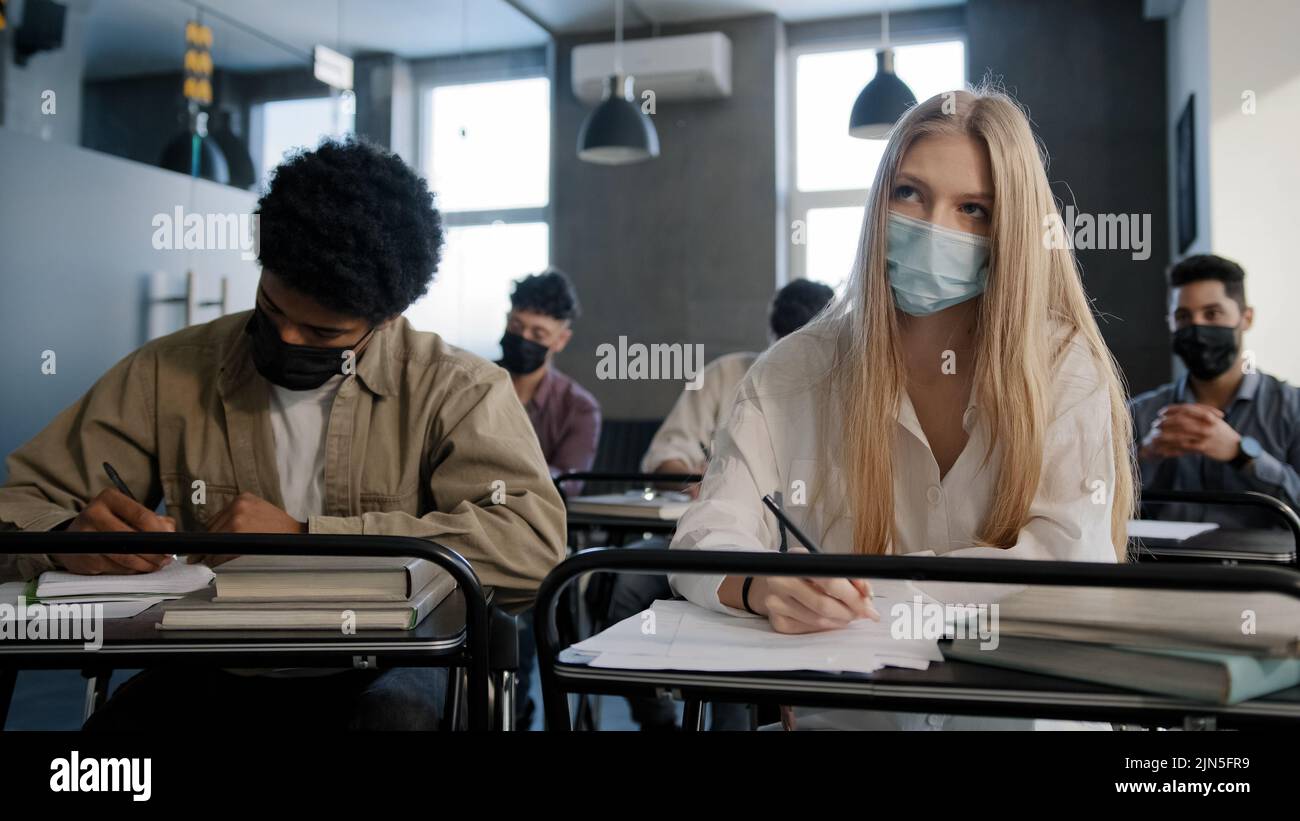 Diverse students in medical mask sit in classroom at lesson ...