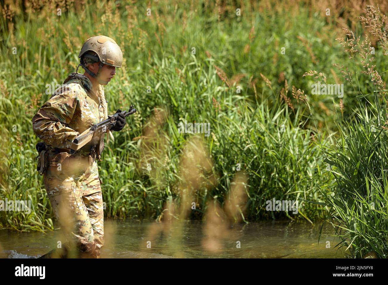 Portrait of fit military female holding weapon rifle in hands in river ...