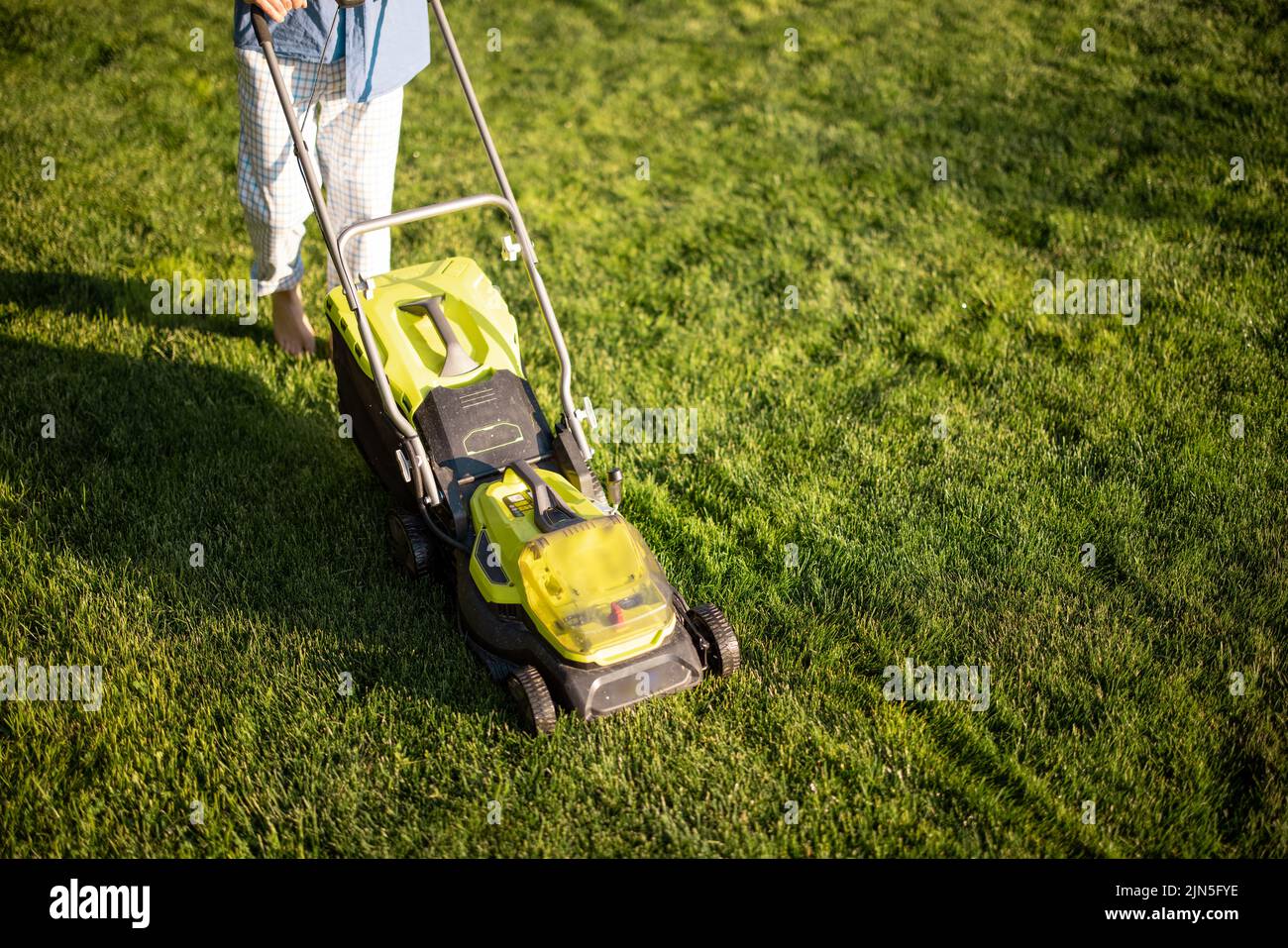 Man mows the lawn with lawn mower at backyard Stock Photo - Alamy